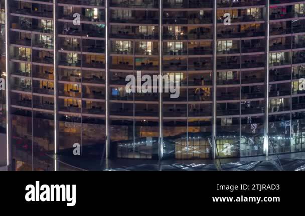 Illuminated panoramic windows in apartments of a high class building at ...