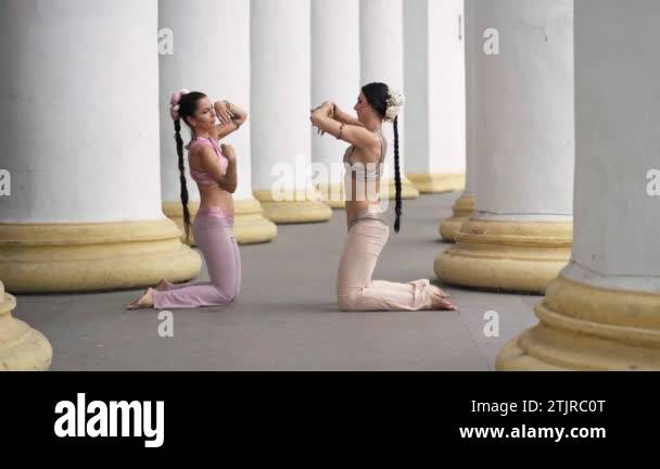 Two talented gorgeous women bending on knees standing up turning performing Indian dance at ...
