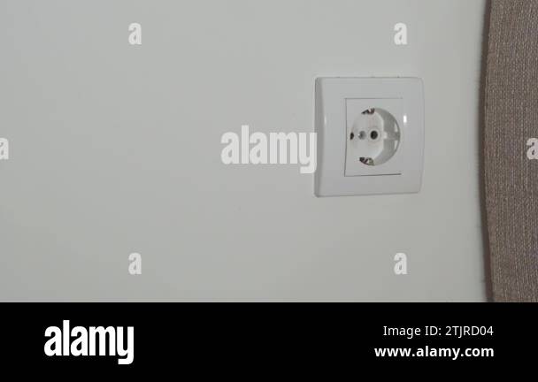 A close-up of a mans hand inserts a black wire to power a white rosette ...