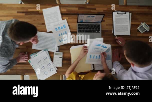 Table full of statistic papers shown on charts and hands of different ...