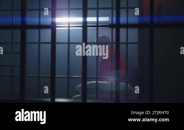 Elderly Criminal In Orange Uniform Sits In Jail Cell Stands Up And