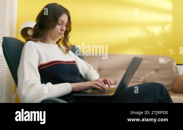 Profile shot of young attractive lady typing on laptop sitting in ...