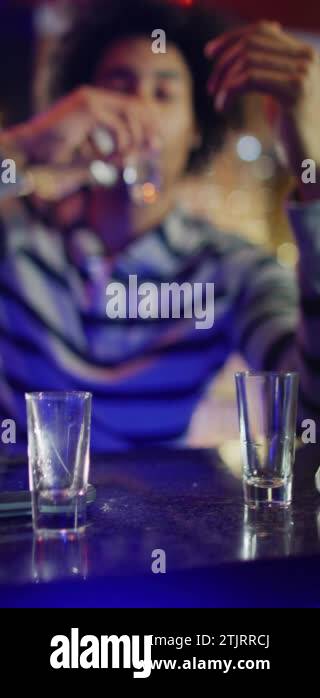 Vertical video of drunk african american man sitting at a bar drinking ...