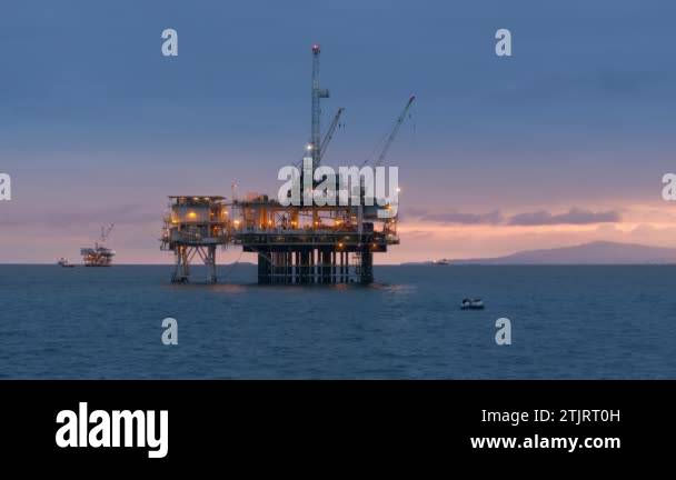 Large illuminated oil drilling rig with several ships on the background ...