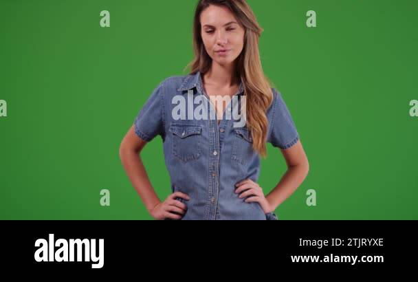 Attractive female millennial standing with hands on hips on green ...
