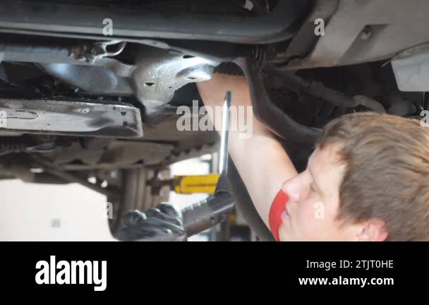 Auto mechanic inspecting bottom and suspension of a car at garage ...