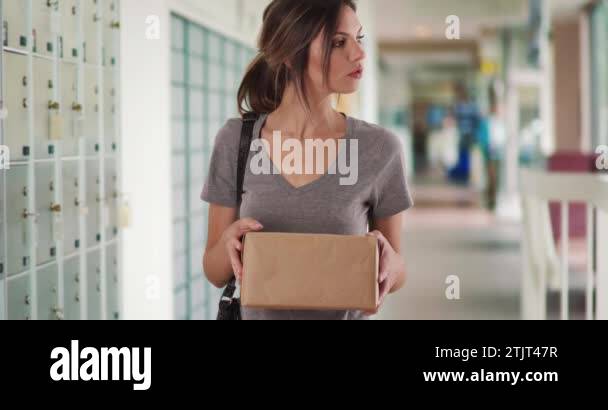 Woman reading address on parcel and walking off screen by lockers in ...