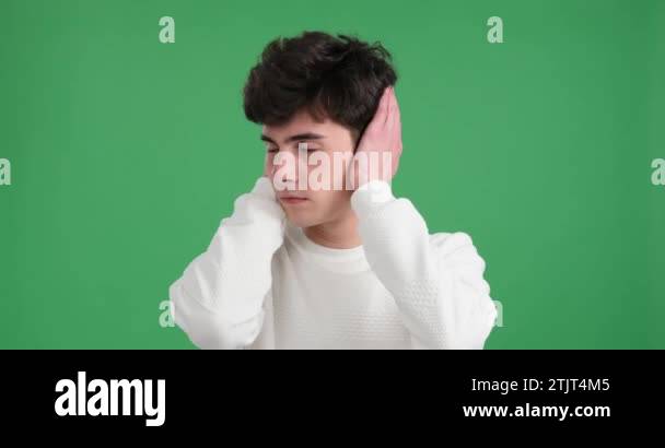 Serious Caucasian man firmly covers his ears with his hand against a ...