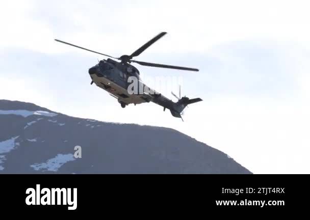 Military helicopter in flight at high speed in a narrow mountain valley ...