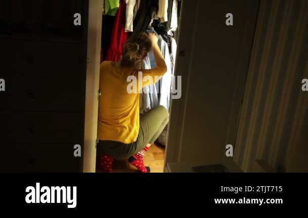 Woman housewife sorting clothes in closet. Person sit squatting with ...