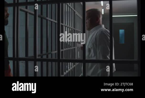 Angry prison officer watches criminals in prison cells, speaks with ...