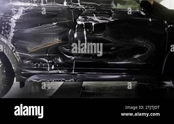 carwash of luxury black car, wash off the foam with pressurized water ...