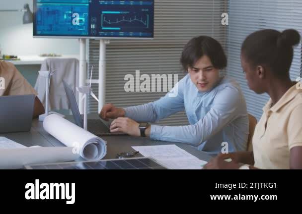 Two young diverse engineers having discussion on environmental project ...