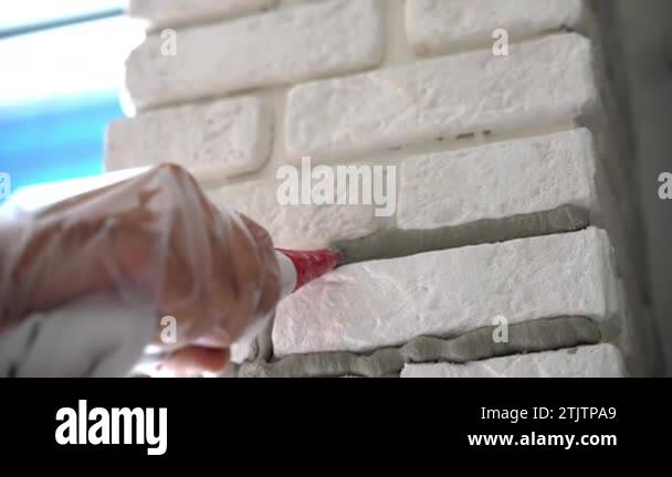 Working process on construction site, workman filling wall joints gaps ...