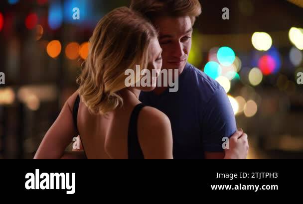 Close up of couple embracing with faces pressed together on urban ...