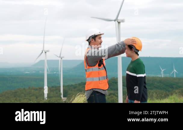 Engineer with his son on a wind farm atop a hill or mountain in the ...