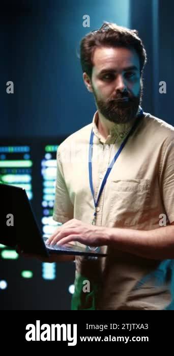 Vertical video Programmer doing annual system examination, checking data on laptop of needed ...