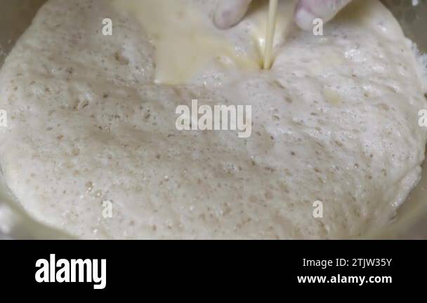 Female Hand Stirring Foamy Yeast Dough in Bowl with Addition of Melted ...