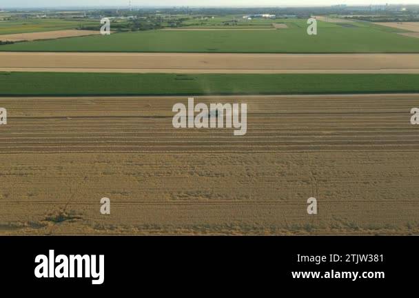 Aerial side view, camera panning lateral, agricultural harvester ...