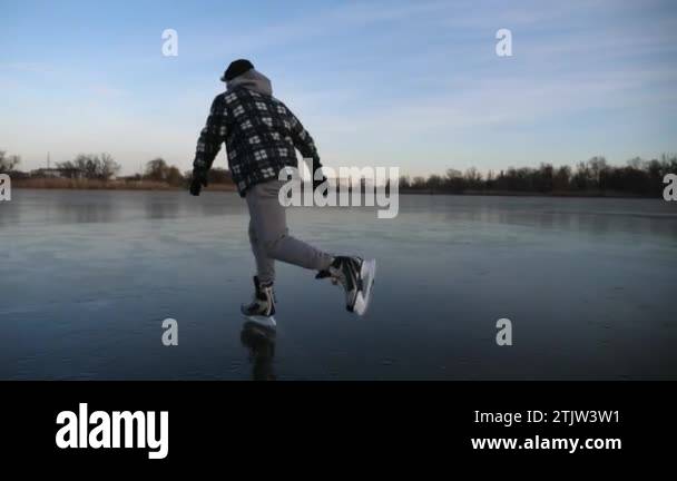 Young man skating on frozen lake covered by ice. Male sportsman ...