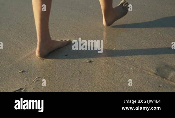 POV: Looking down at your bare feet as you walk along the white sand ...
