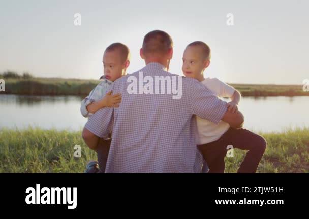 Caring father hugs little boys siblings with Down syndrome sitting on ...