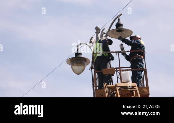 repair street lamp, lift bucket, fix light. Worker is fixing street ...