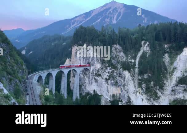 A local train of Rhaetian Railway coming out of the tunnel in a cliff ...