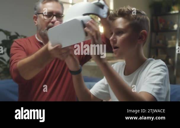 Father helping son to put on VR headset while playing game in augmented ...