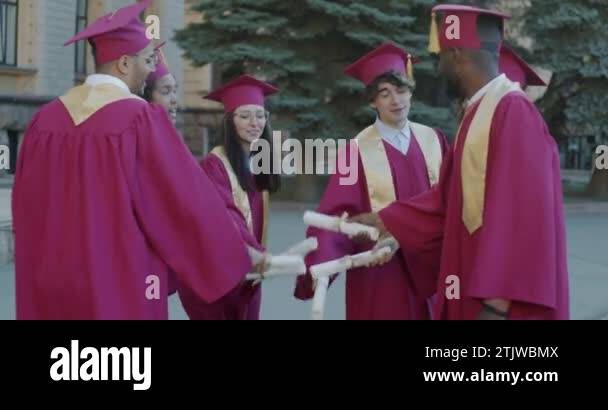 Multi-ethnic group of graduates joining hands with diplomas and ...
