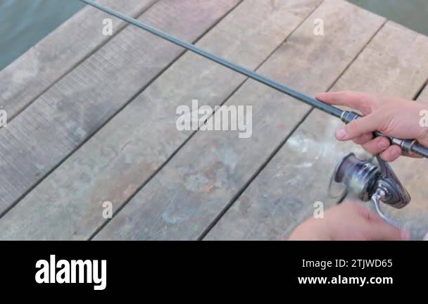 Fisherman holds a fishing rod in his hands and turns the reel standing ...