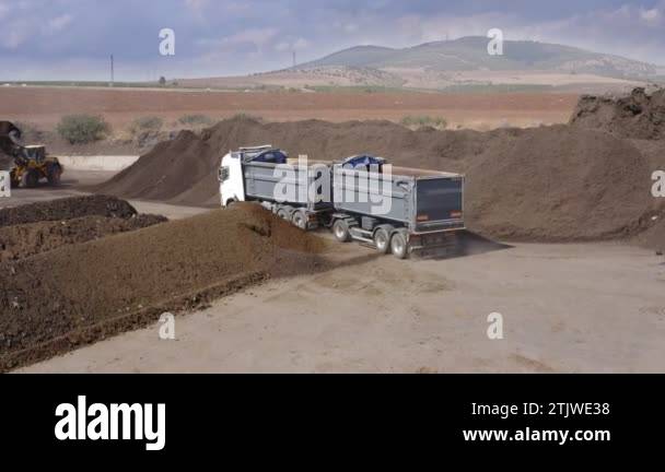 Industrial compost production site. Machines screening compost piles ...