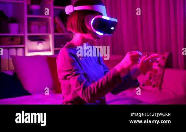 Pretty teenage girl wearing virtual reality headset in a dark room. Cute teen using VR glasses ...