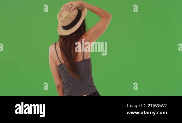 Attractive young white woman dancing while facing green screen wall ...