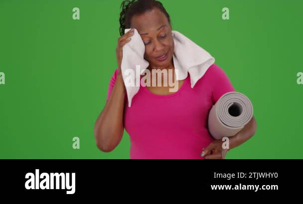 An elderly African American woman poses for a portrait as she wipes her ...