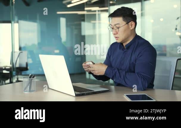 Sick businessman IT programmer blowing running nose sneeze and cough while working on laptop ...