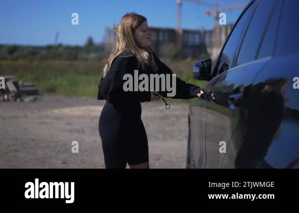 Nervous desperate young woman pulling car door failing to open vehicle sighing leaning on ...