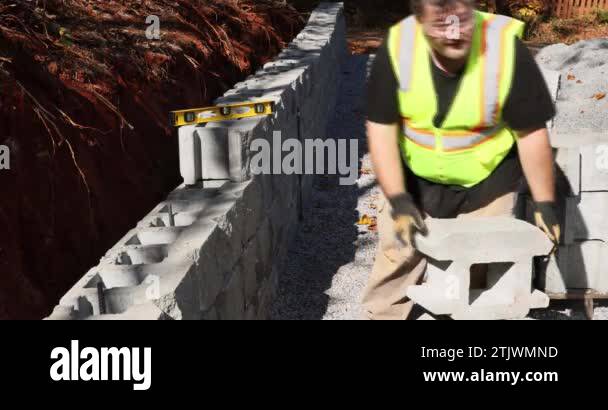 Contractor during installation of new large block retaining wall in ...