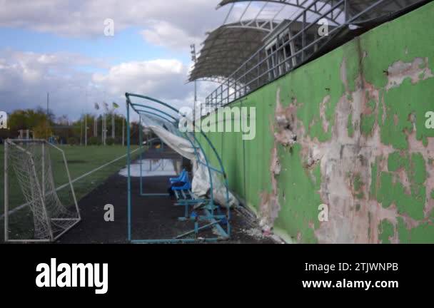 Side view ruined spectator seats on sports field at damaged wall ...