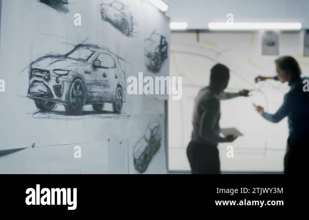 Two diverse automotive male engineers discussing sketch, drawing with ...