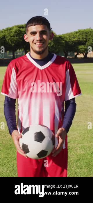 Vertical video of biracial football player with ball on field. Male ...