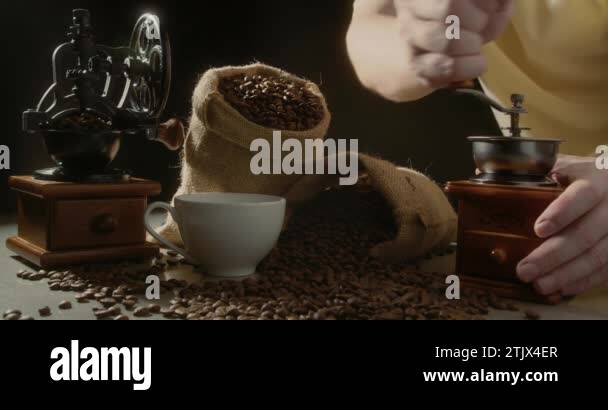 Man grinds coffee beans through manual coffee grinder. Hot cup and ...