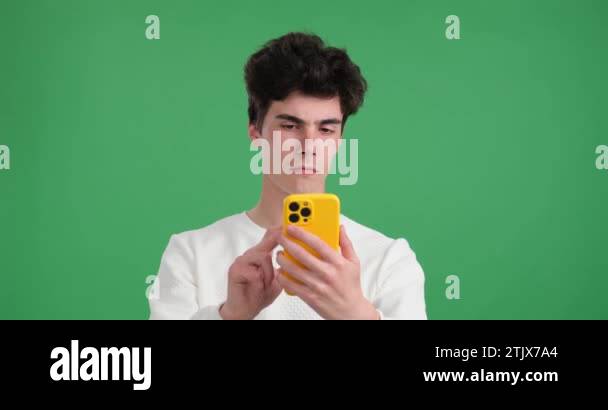 Man as he scrolls through his phone, set against a vibrant green ...