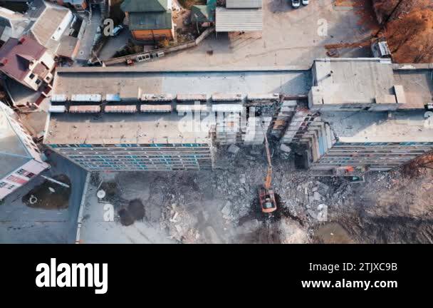 Natural disaster demolition building. Excavator at a construction site ...