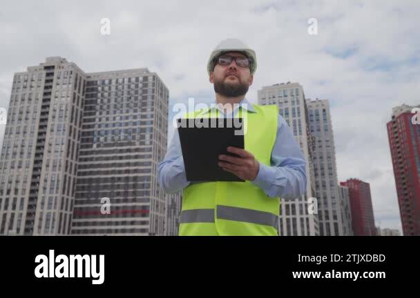 Building inspector wearing helmet and safety vest holding file folder ...