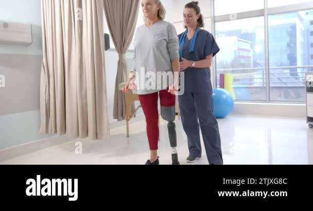 Caucasian female physiotherapist and female senior patient with prosthetic leg exercising ...