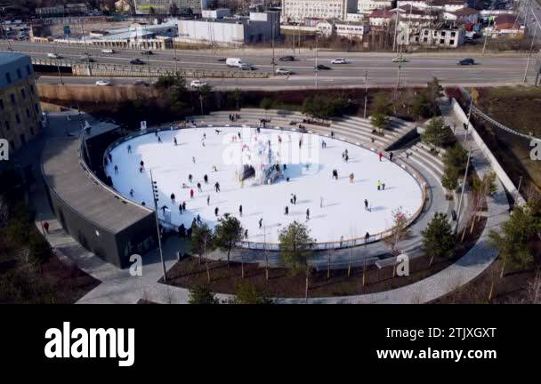 City view open air skating rink, road bridge and passing cars, lot ...