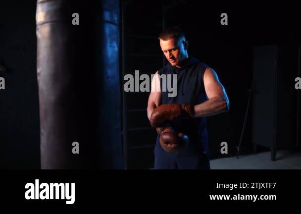 Male boxer putting on boxing gloves in gym against background of ...