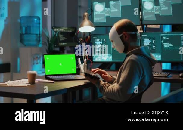 Impostor with mask hacking network with greenscreen on laptop, breaking ...