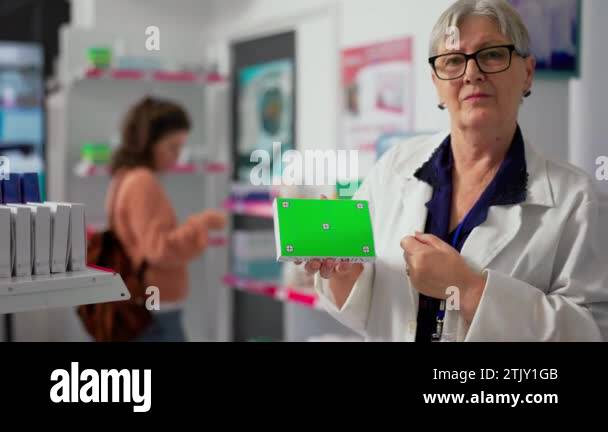 Pharmaceutical worker holding greenscreen on box of pills, female ...
